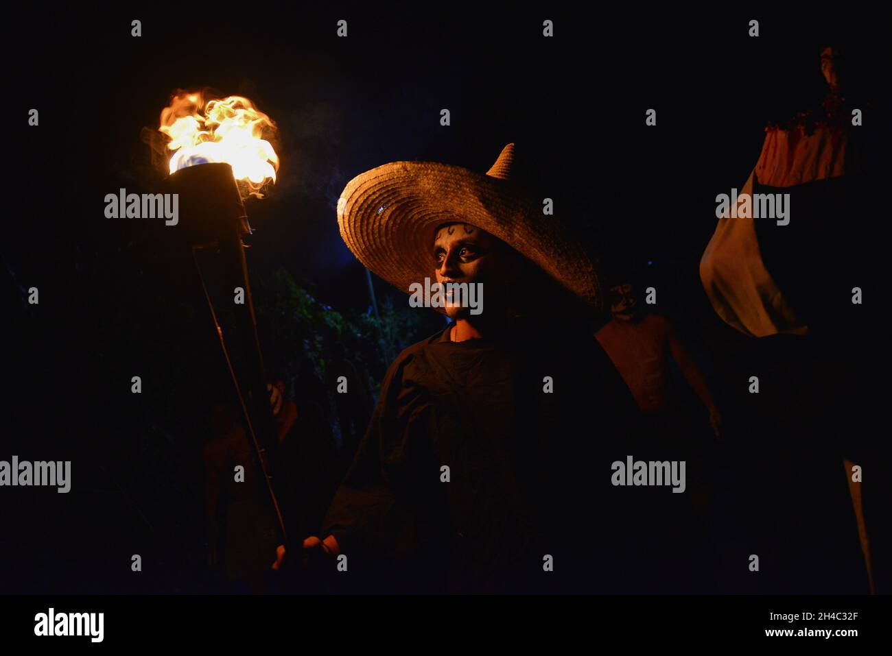 A reveler looks on while holding a torch.Salvadorans celebrated ...
