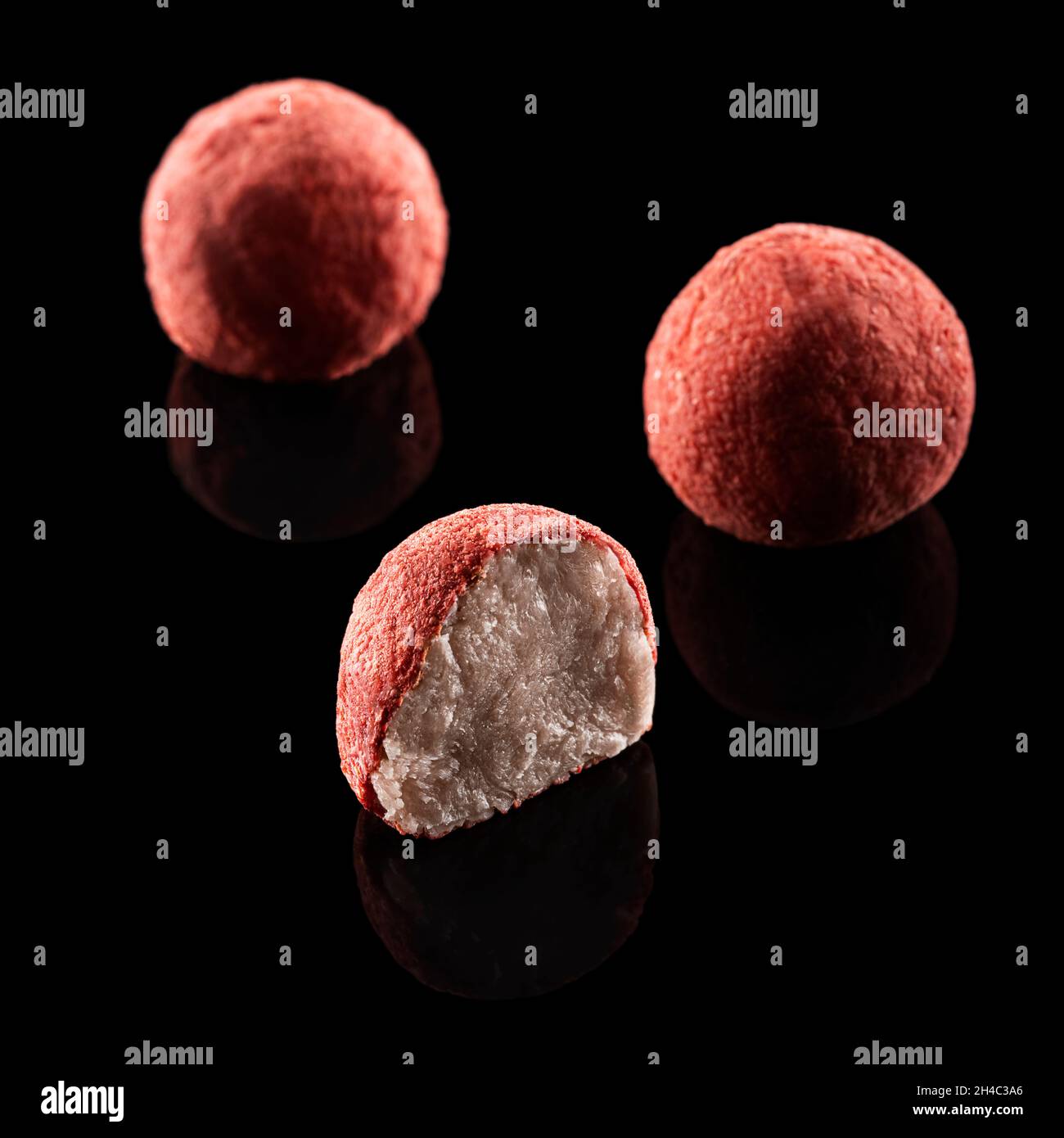 Three strawberry truffles with filling. Isolated on a black background ...