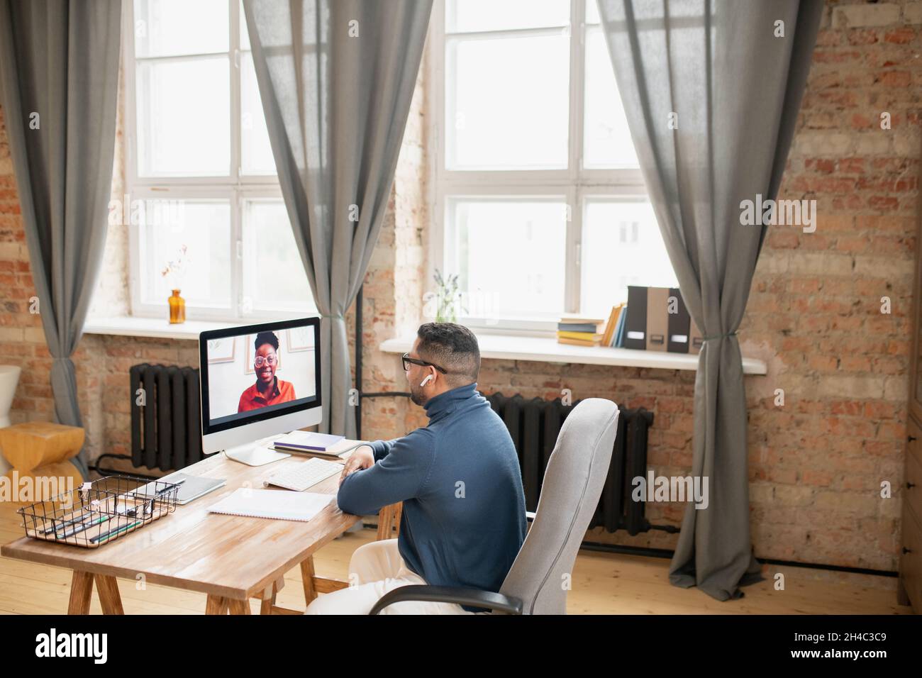 Contemporary teacher sitting by workplace in front of computer monitor ...