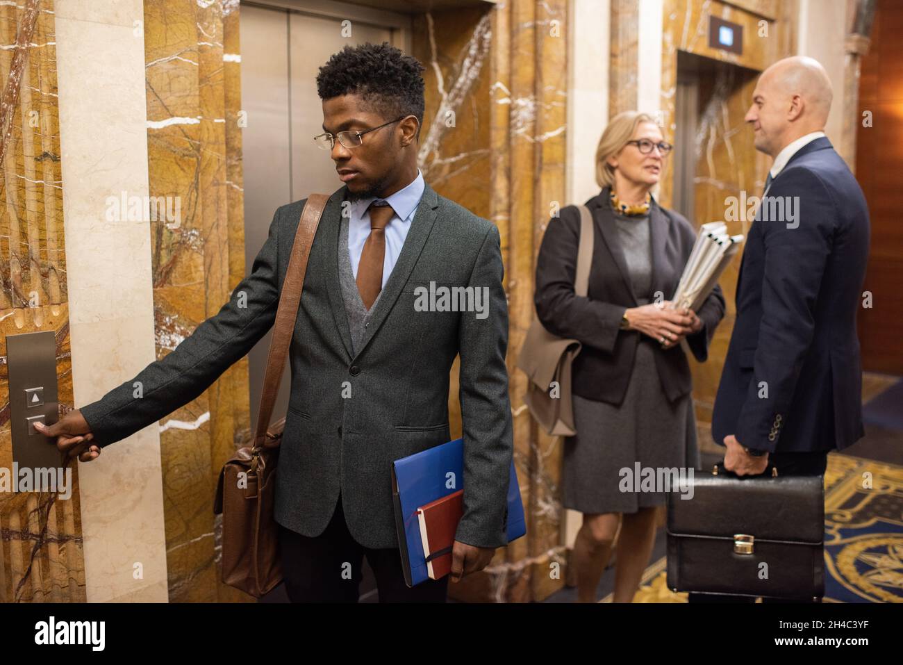 Young elegant businessman pushing elevator call button while standing ...