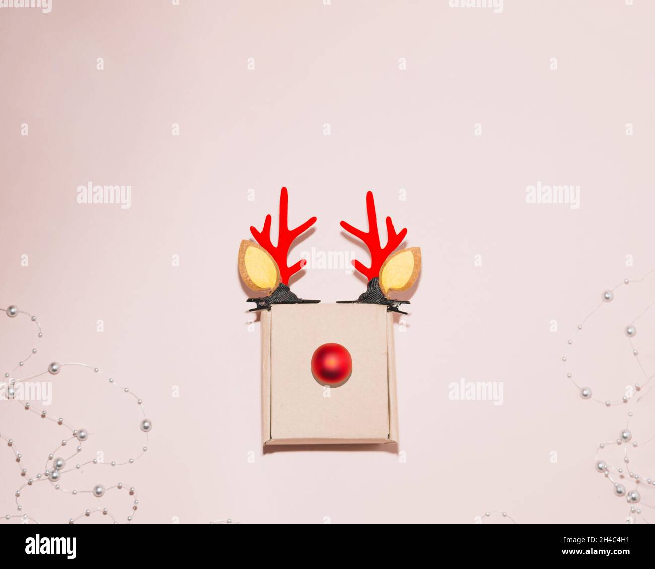 Layout with cardboard box with reindeer horns and red nose on pink ...