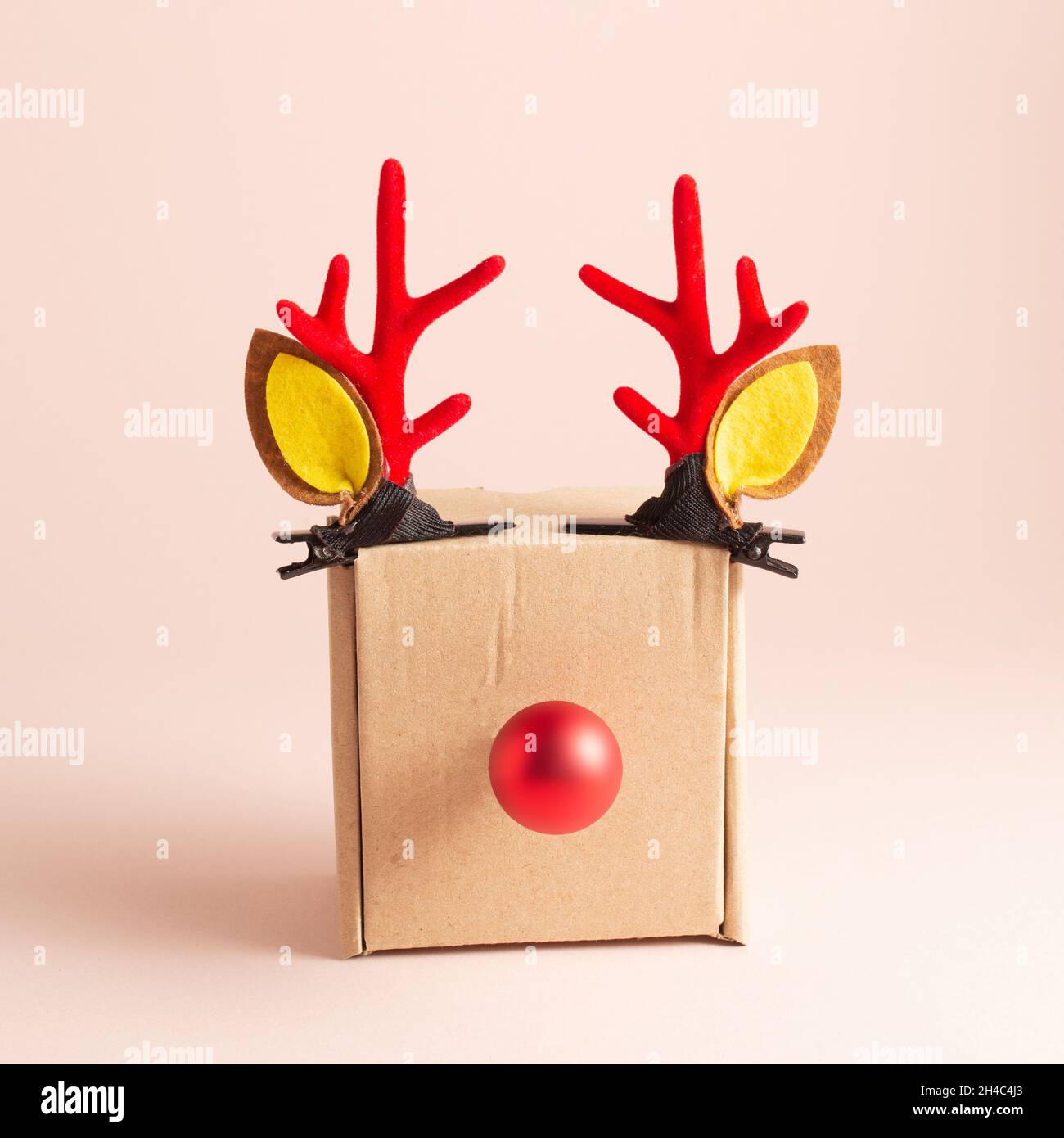 Cardboard box with reindeer horns and red nose on pink background. New ...