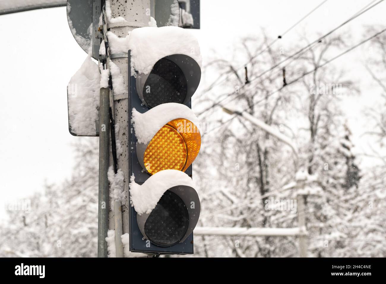 A working traffic light on a city street in winter.The yellow light is ...