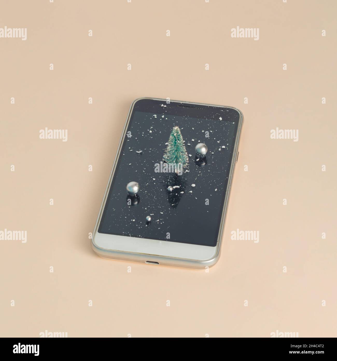 Cell Phone with Christmas tree, snow and shine balls on pink background ...