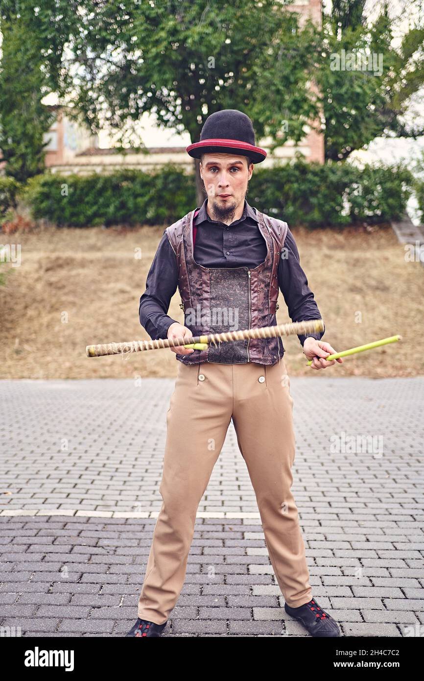 Male performer in fancy suit juggling devil sticks on summer day in ...