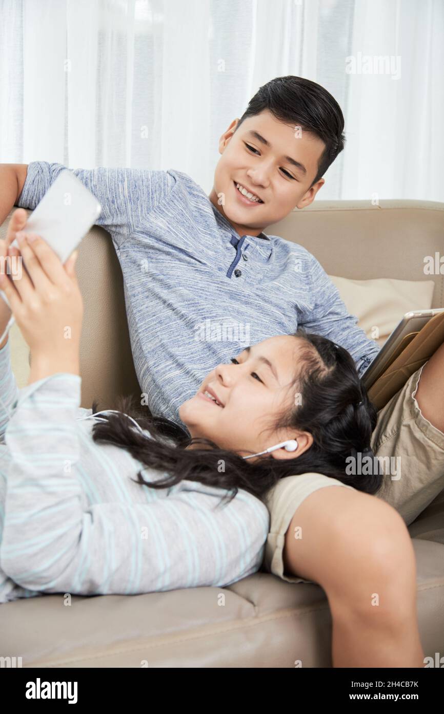 Teenage boy and girl using apps on tablet computer and smartphone to ...