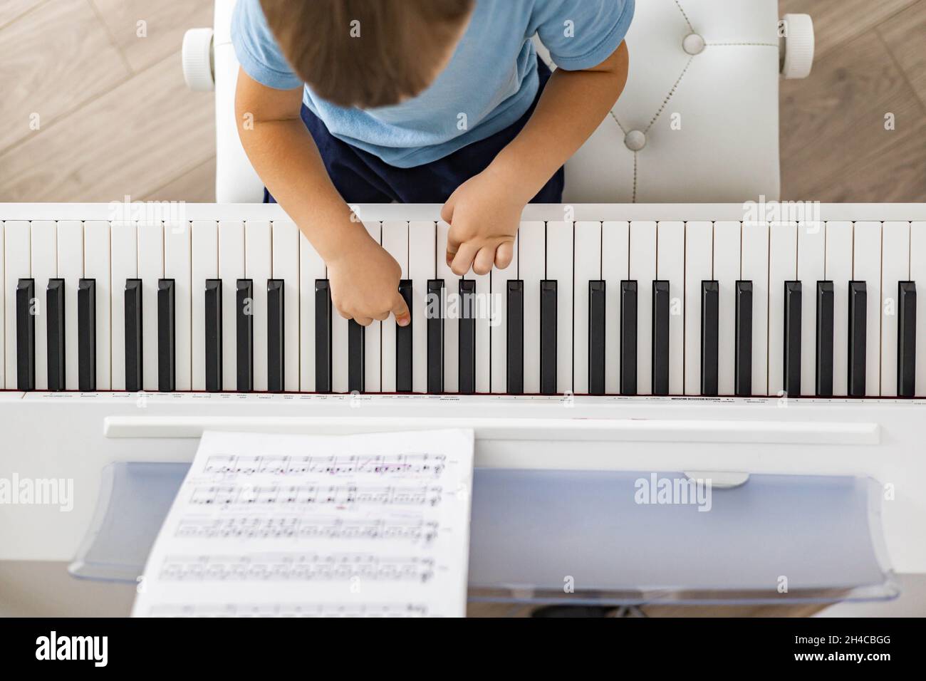 Cute baby boy playing white electrical forte piano pressing keys kid ...