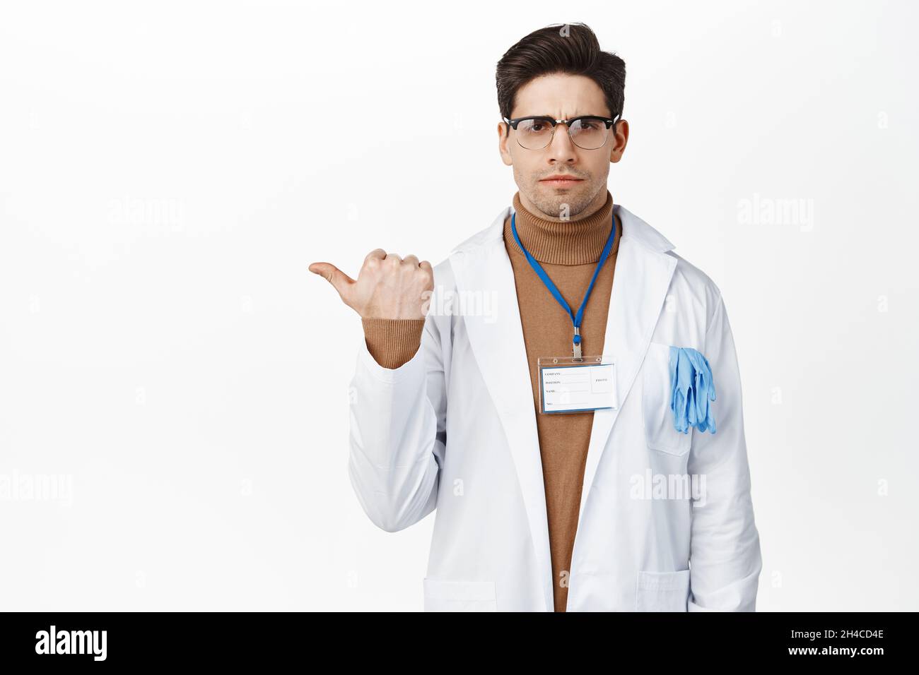 Displeased male doctor, physician pointing left and furrow eyebrows ...
