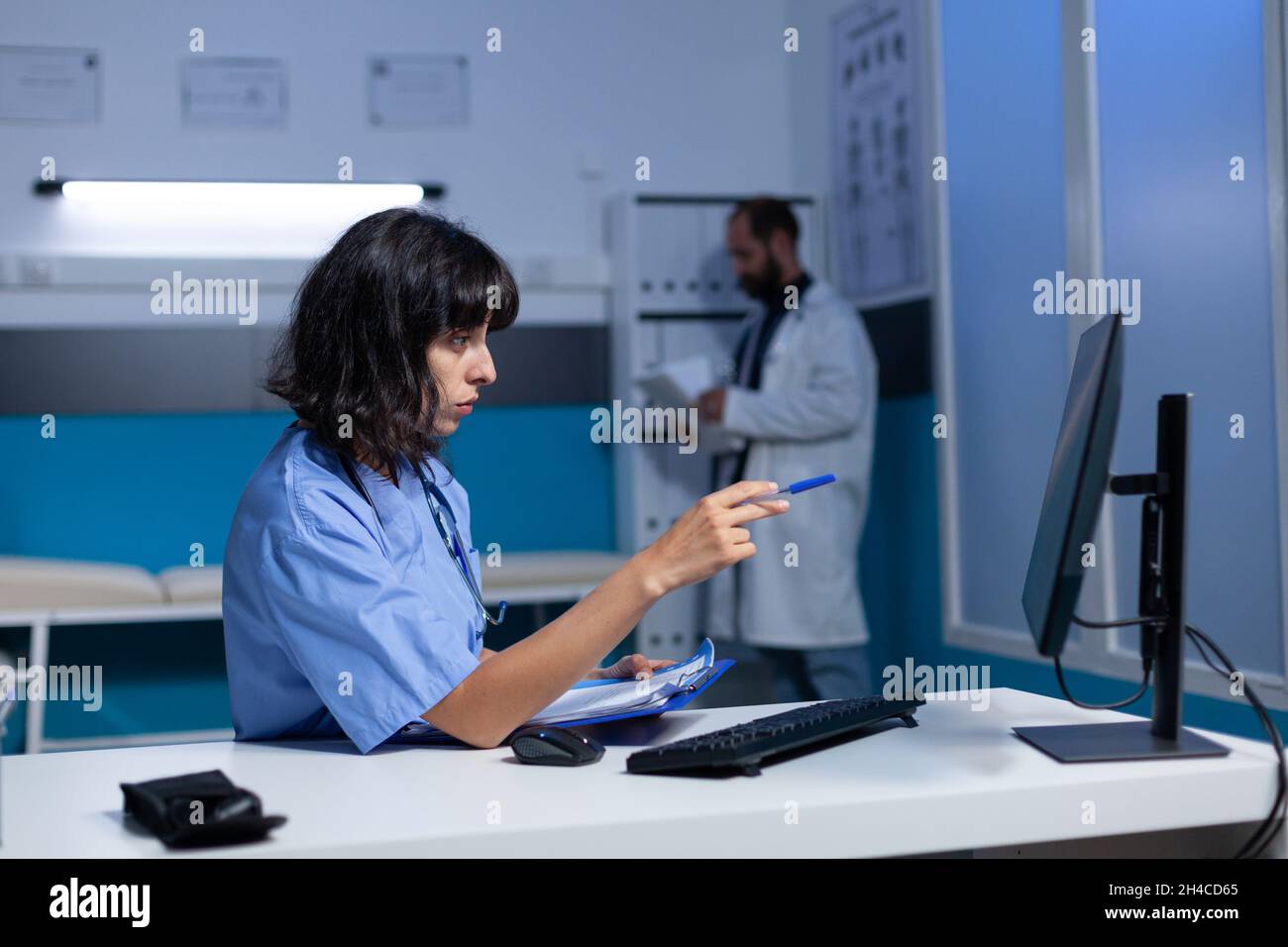 Nurse doing overtime work with computer and checkup files at office ...