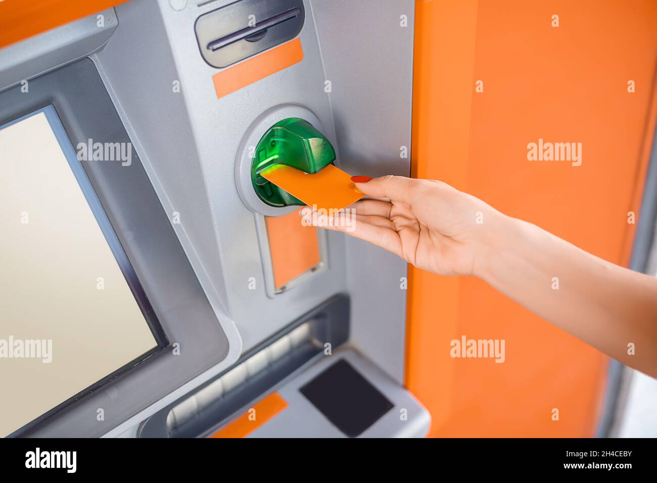 Close-up of a woman inserting a credit card into a bank ATM machine ...