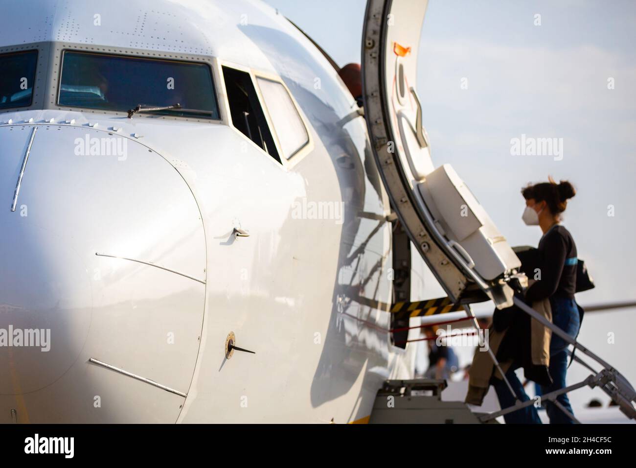 People boarding an airplane at the airport. Focus on the nose of the ...