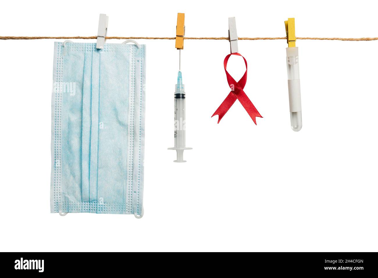 Red ribbon, syringe, and face mask hanging on the rope with white ...