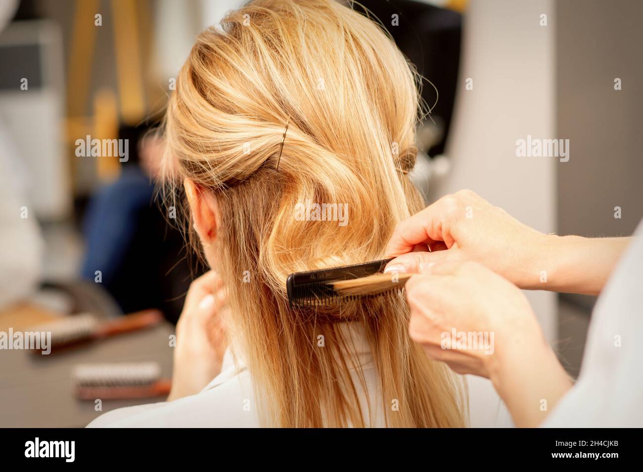 A hairdresser is combing female hairstyling in a hairdressing beauty ...