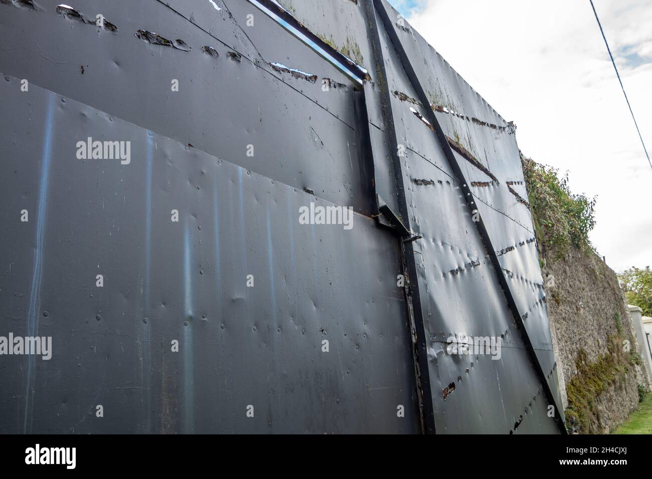 Old wobbly black metal gate with holes Stock Photo - Alamy