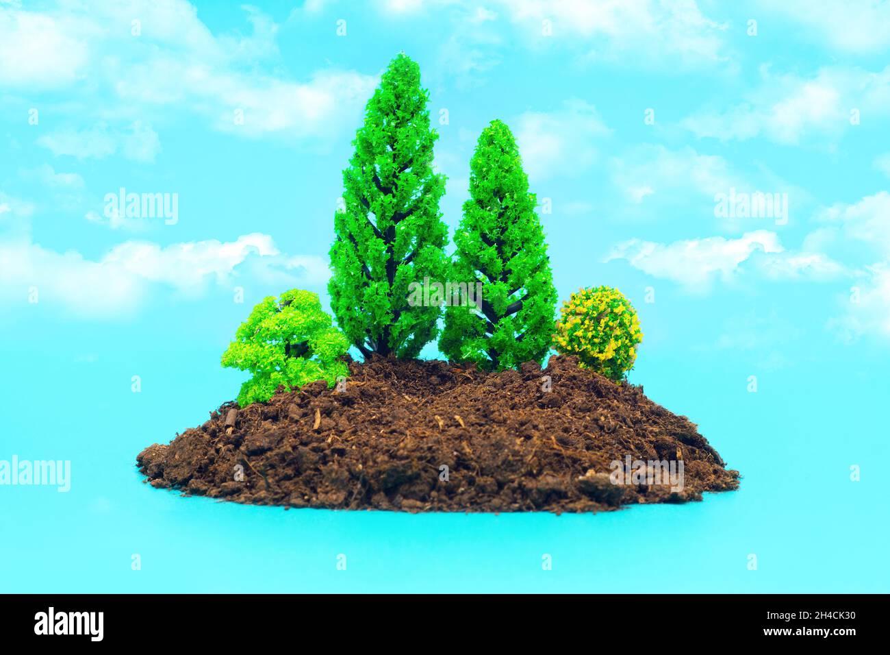 Miniature toy forest setup against a blue sky background. Clean ...