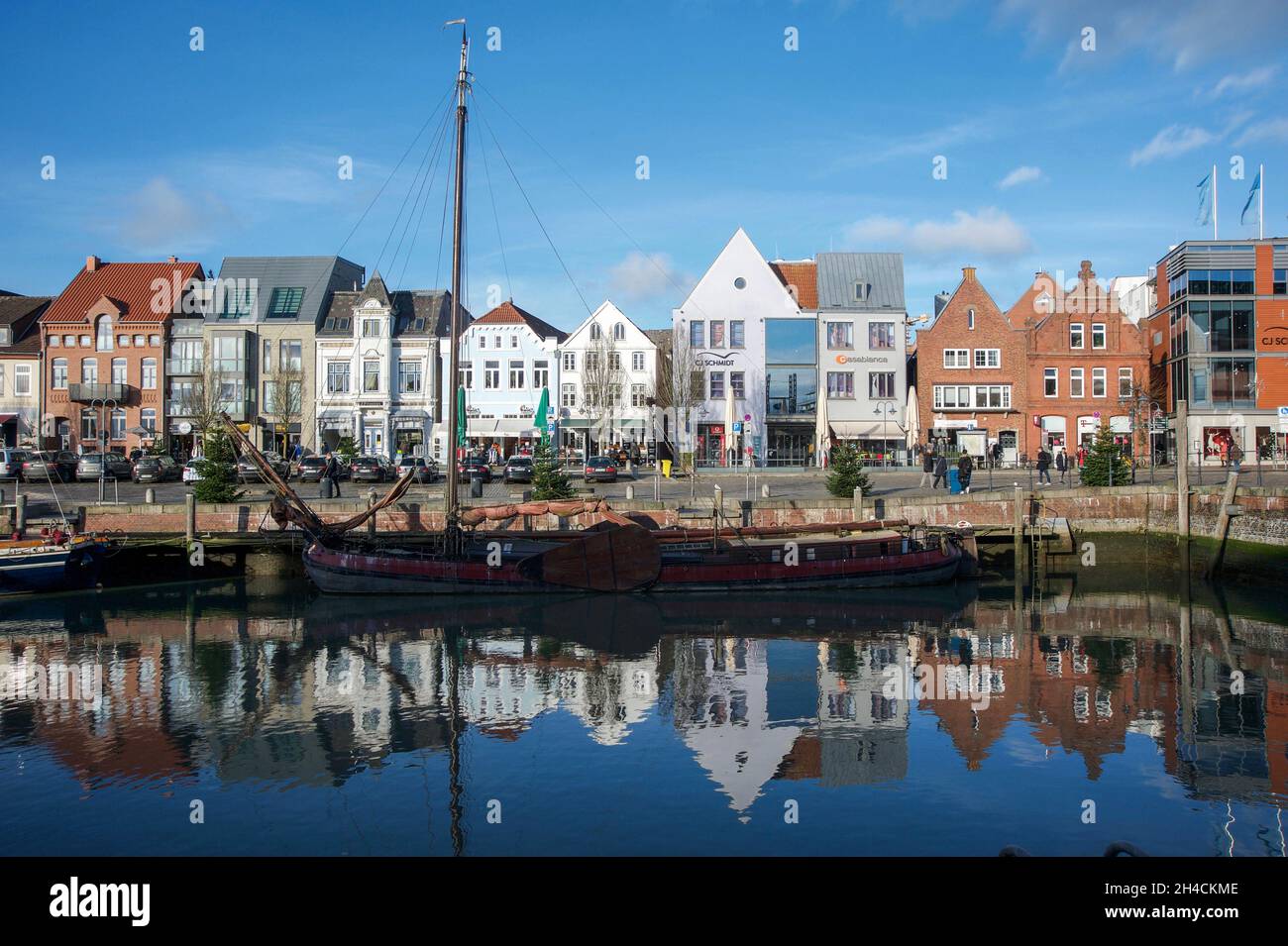 Old buildings and sailing ship reflected in the water. Husum harbour ...