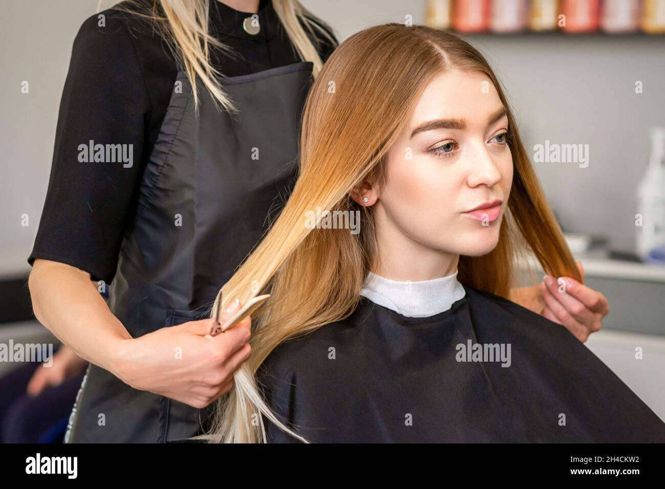 Hair stylist's hands doing professional hairstyling of female long hair ...