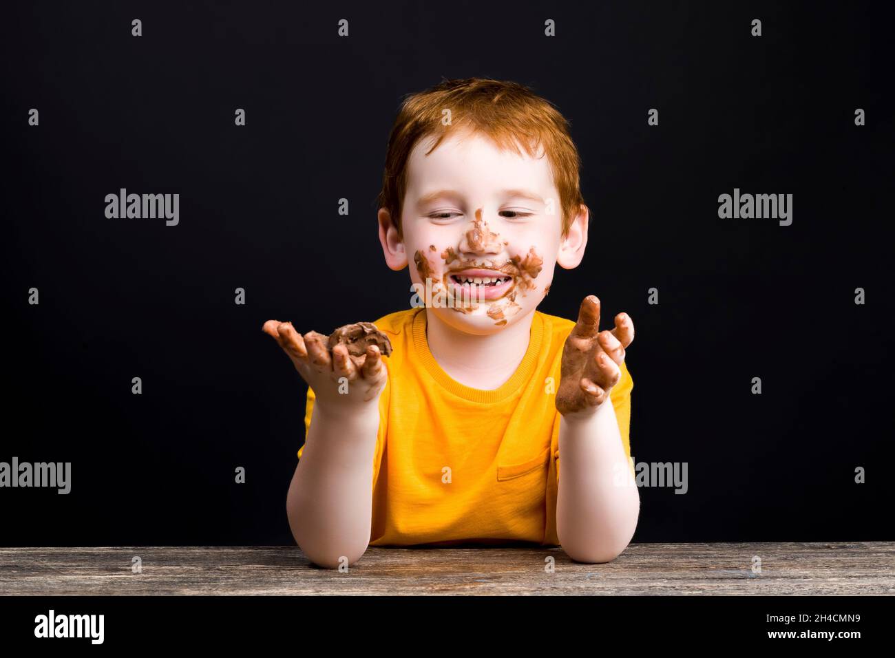 boy smeared in milk chocolate after nibbling and biting real cocoa ...