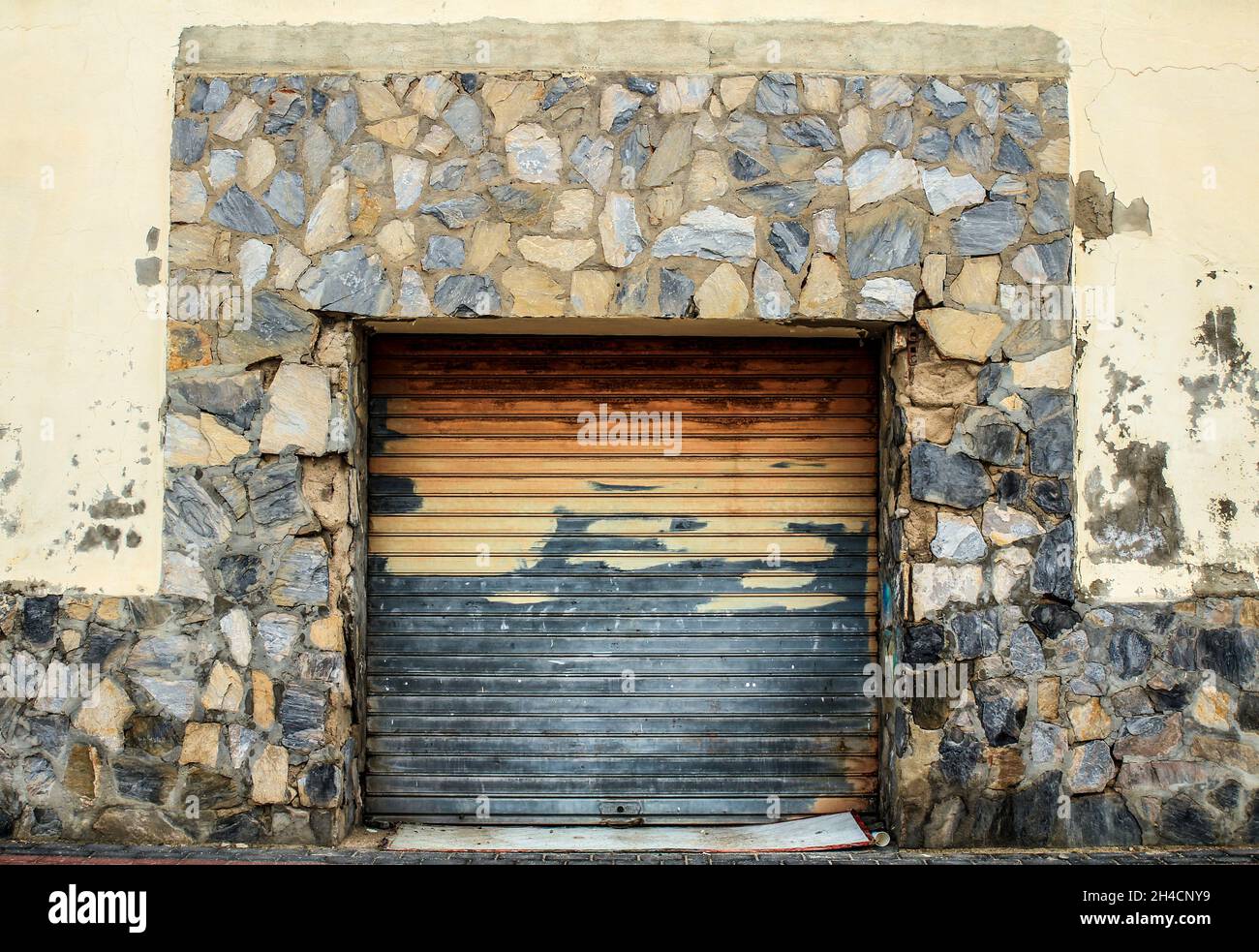 Facade with door with rusty metal door painted yellow in Spain Stock ...