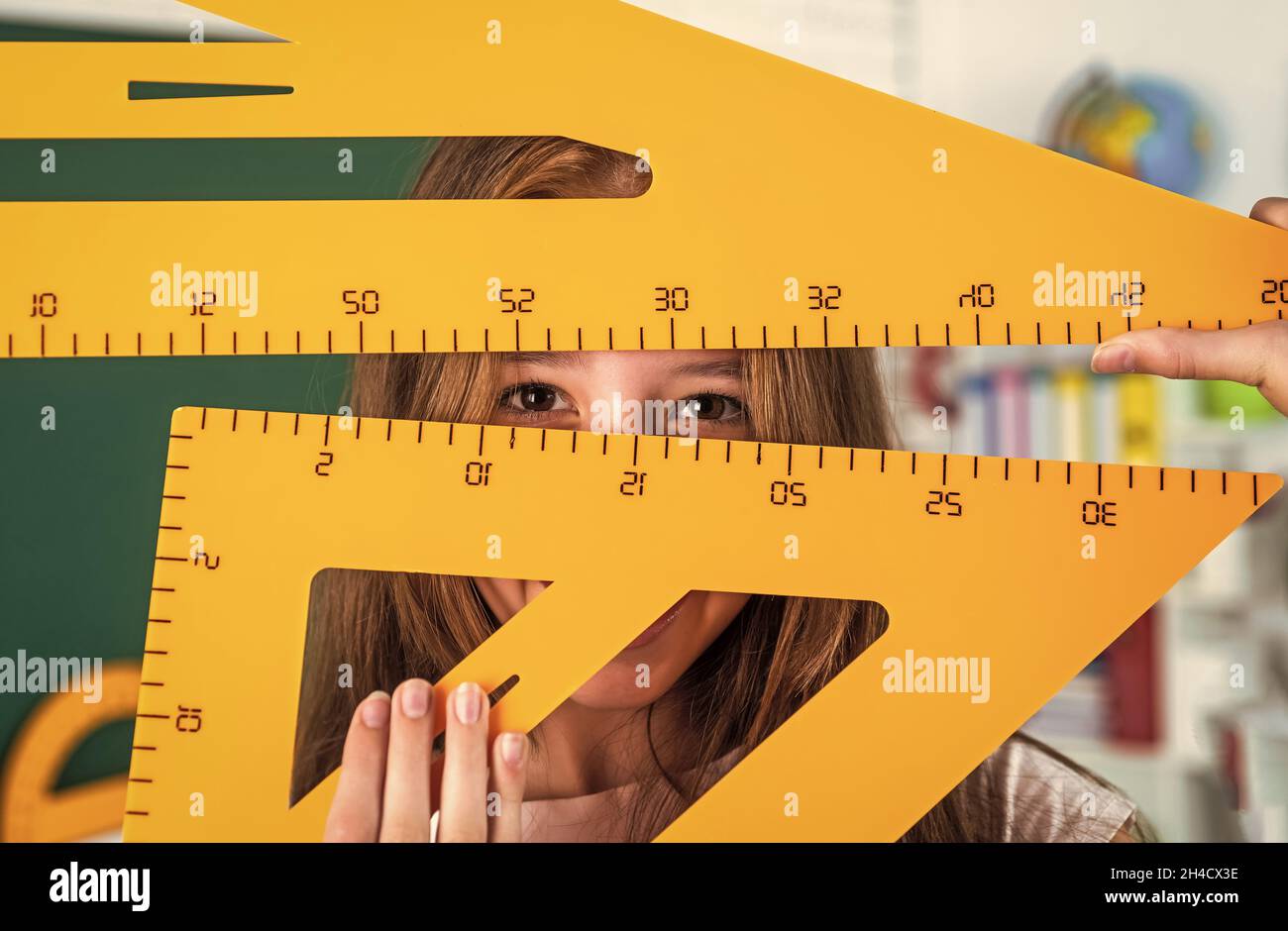 cheerful girl work in school classroom with math triangle tool ruler ...