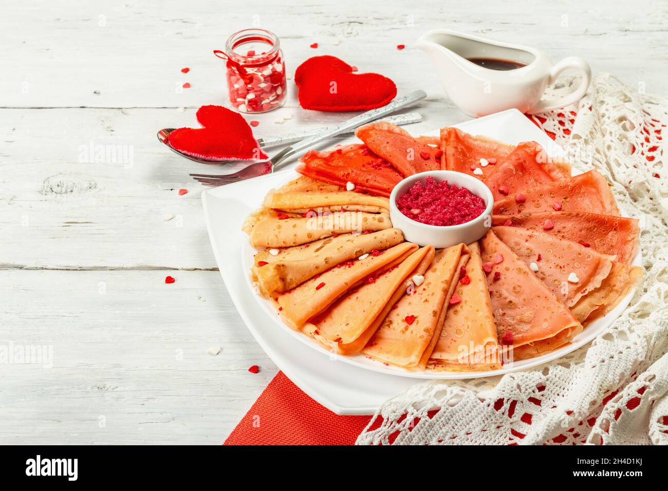 Thin red crepes or pancakes with raspberry sugar and sweet hearts ...