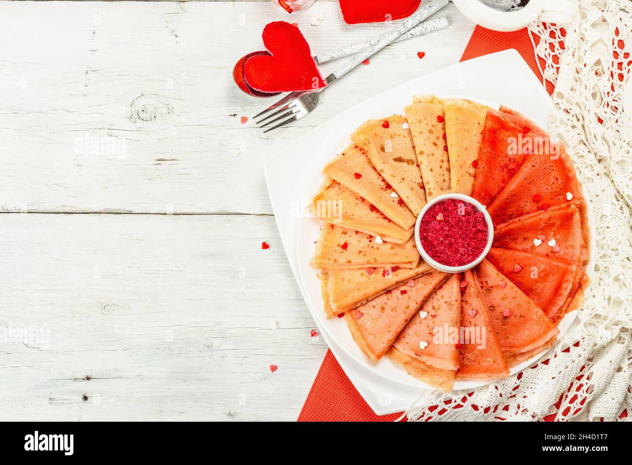 Thin red crepes or pancakes with raspberry sugar and sweet hearts ...