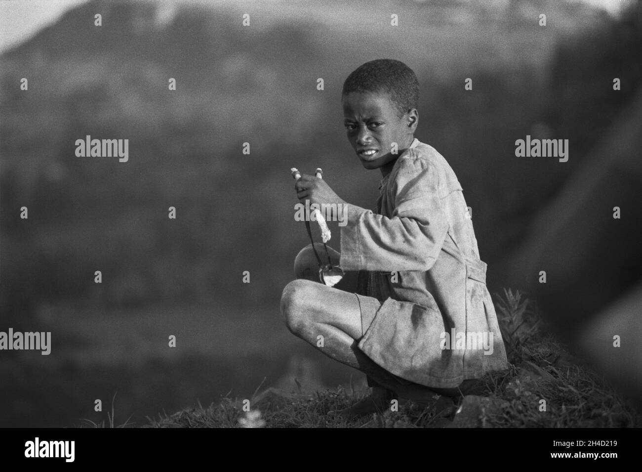 Africa, Ethiopia, 1976. A boy looking aggressive with a loaded catapult ...