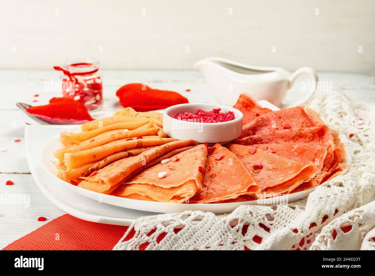 Thin red crepes or pancakes with raspberry sugar and sweet hearts ...