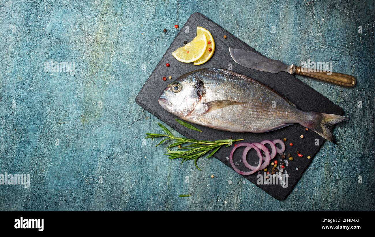 Top view of fresh fish dorado or gilt-head bream with lemon, onion ...