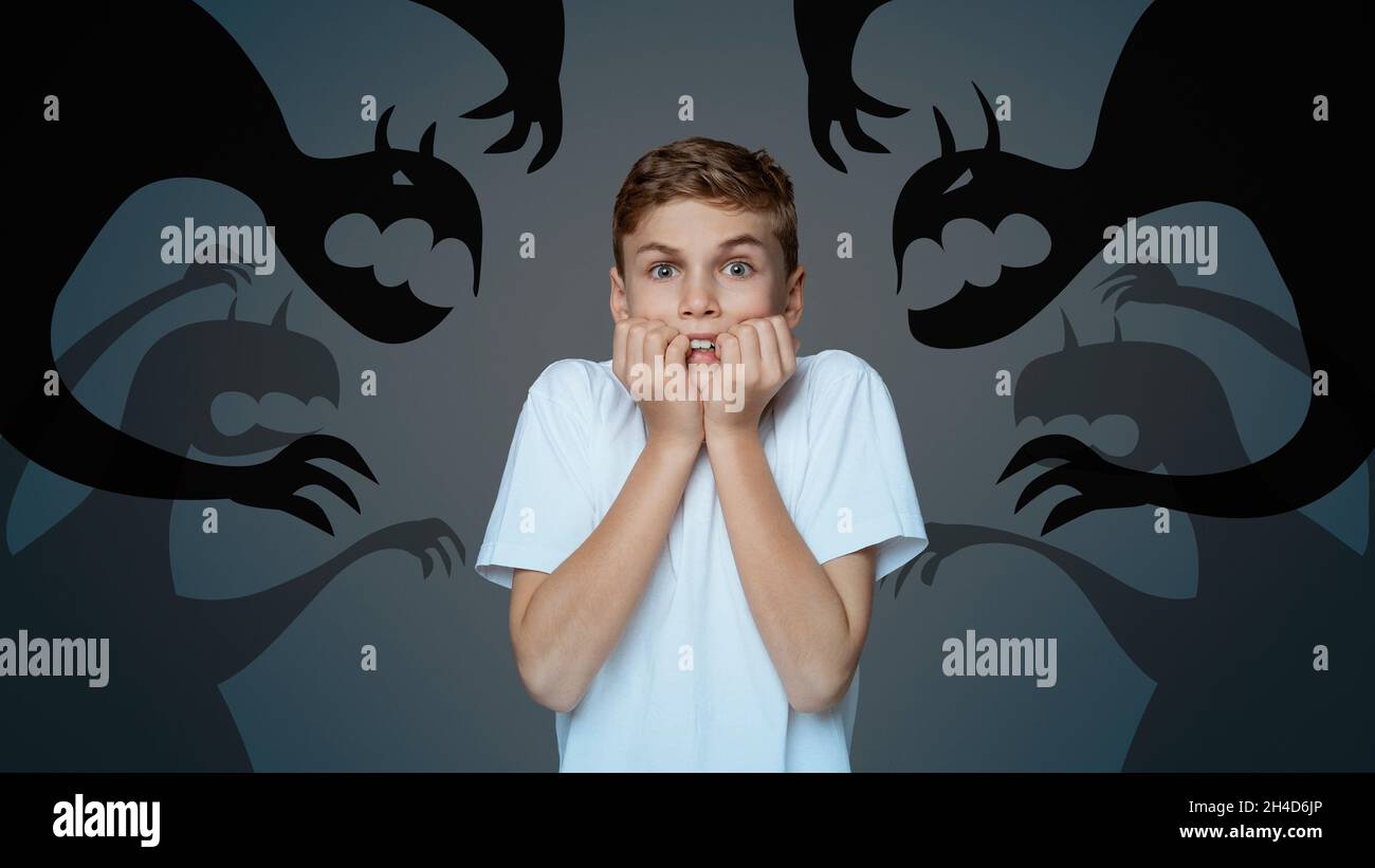 Afraid little boy biting nails in panic, scared of monster shadows on ...