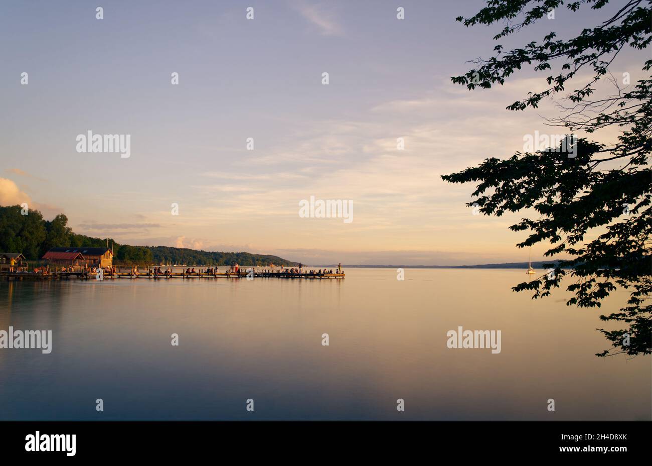 Starnberg, Deutschland . 23rd June, 2021. Einige Personen sitzen im Sonnenlicht auf dem Steg ...