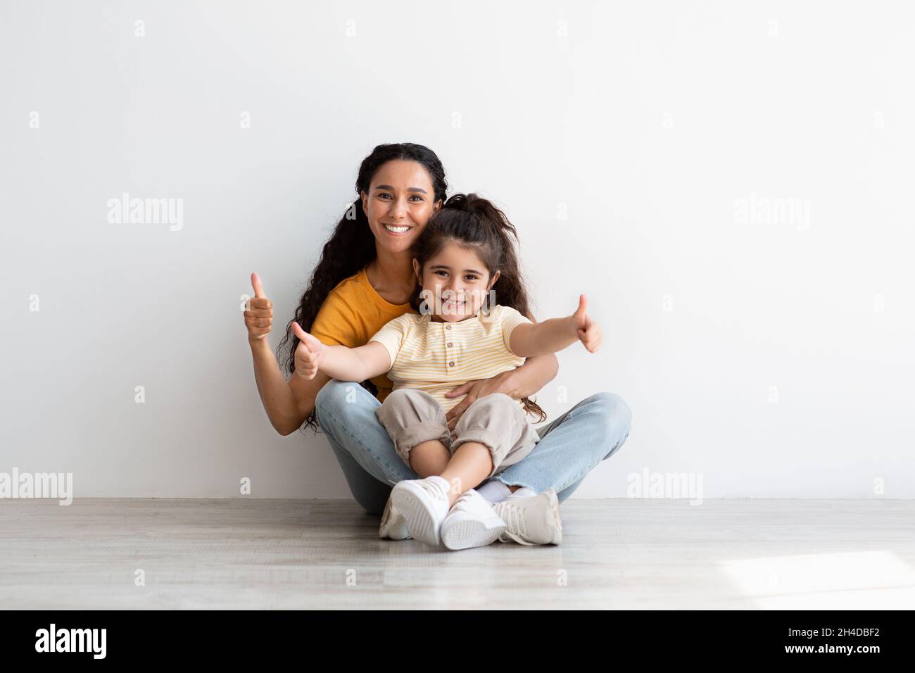 Happy Mom And Little Daughter Embracing And Showing Thumbs Up At Camera ...