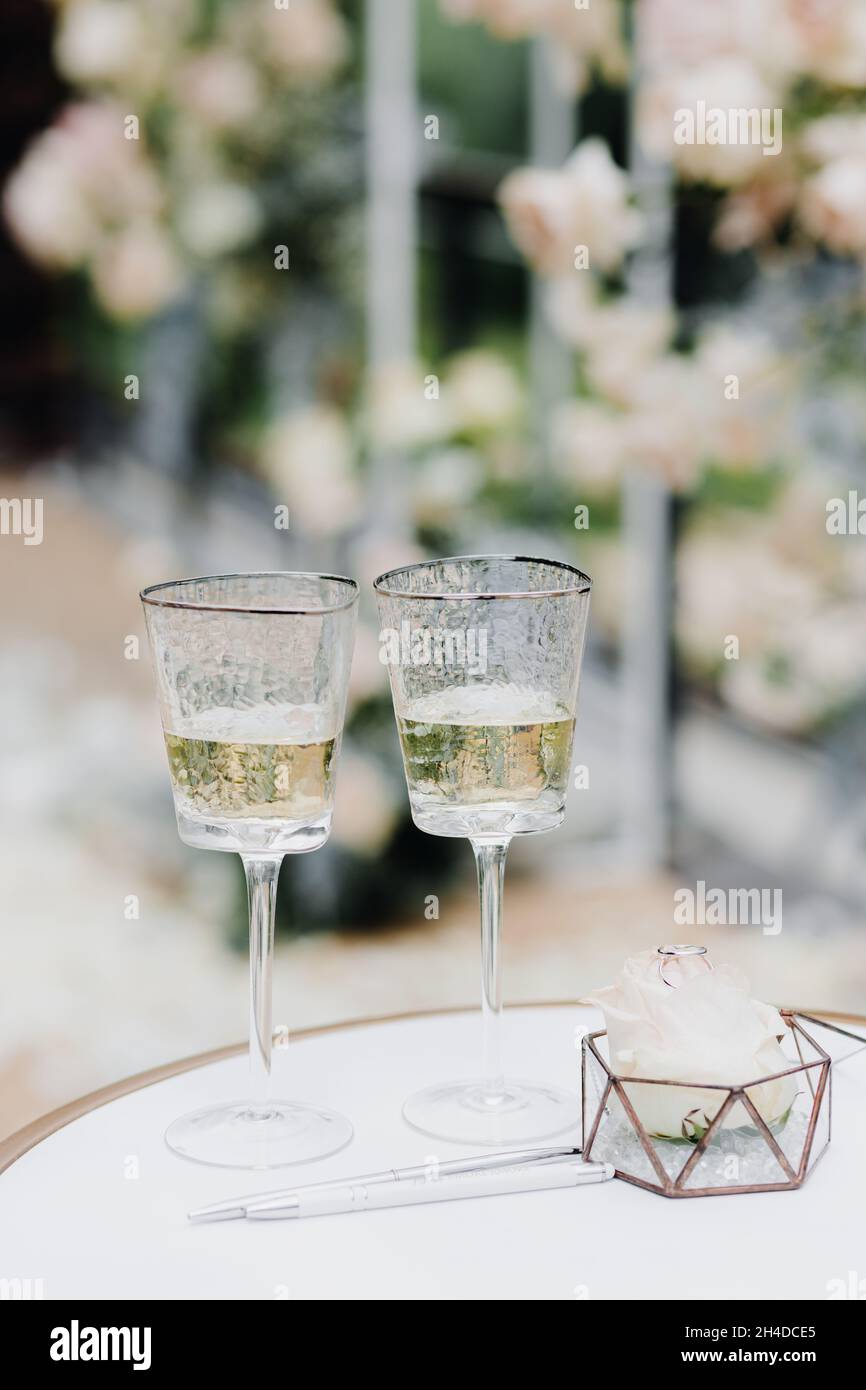 Glasses of champagne and wedding rings on the table for the bride and ...