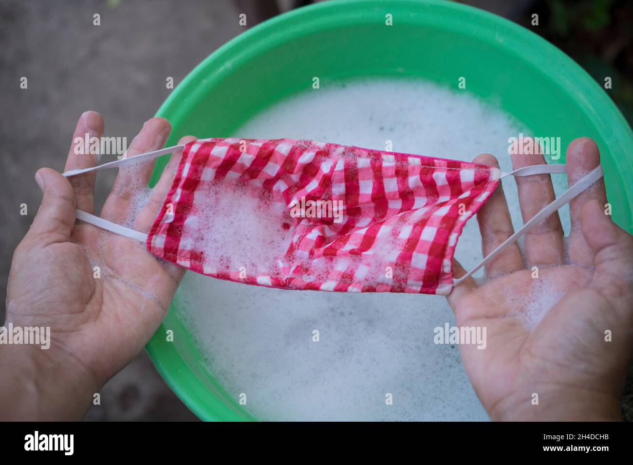 woman hand Washing a mask using detergent dissolved in water. Washing ...