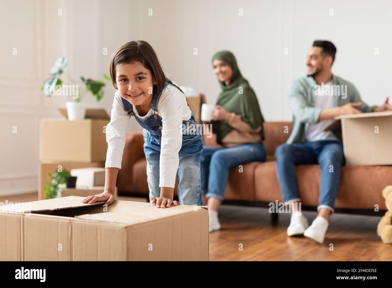 Happy islamic family packing or unpacking boxes, girl pushing box Stock ...