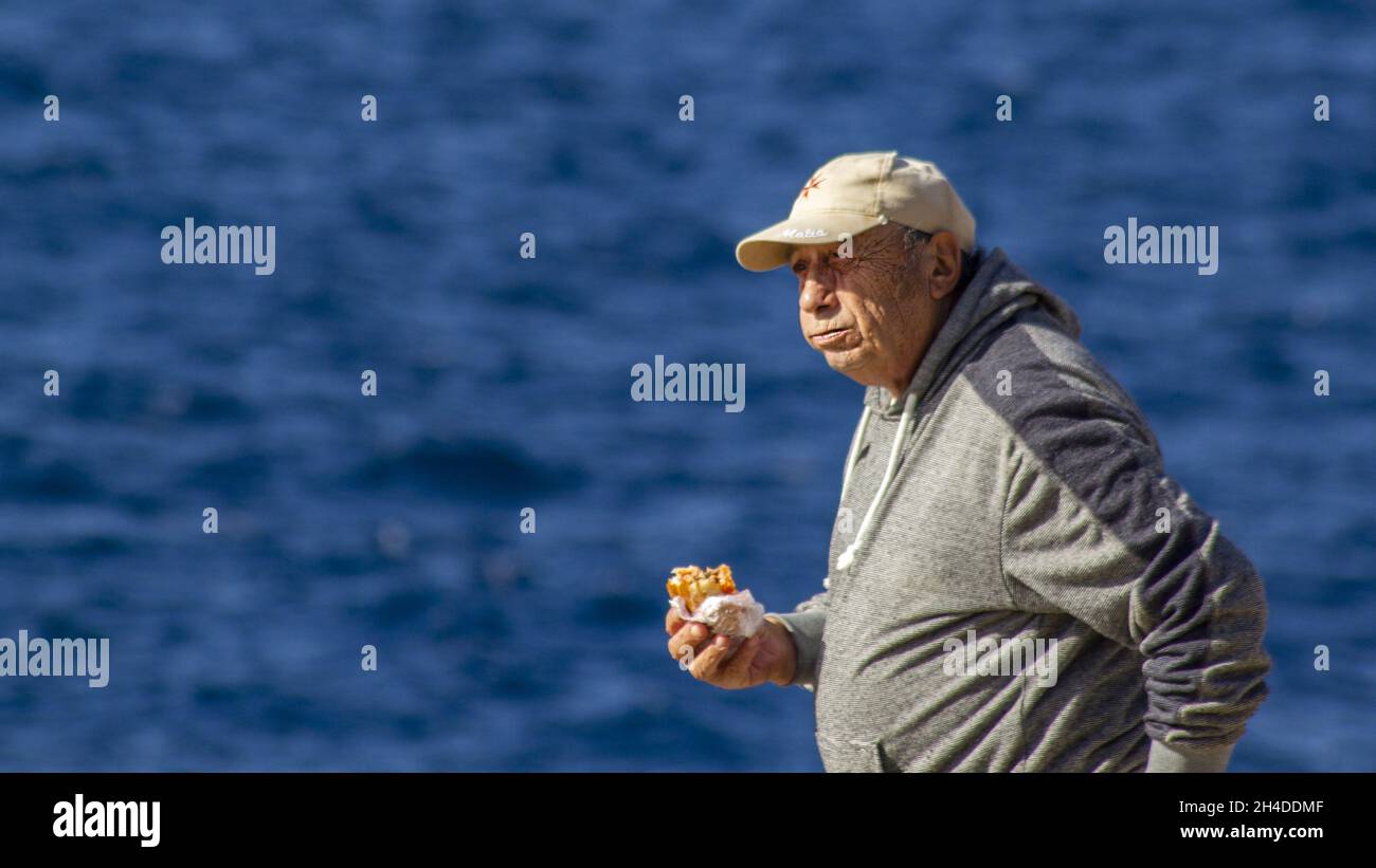 RABAT, MALTA - Jan 06, 2021: Maltese Man eating a typical Hobza biz ...