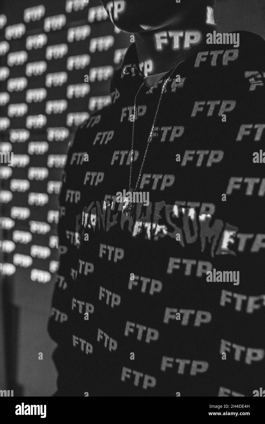 Grayscale of a man standing in front of the press wall with the ...