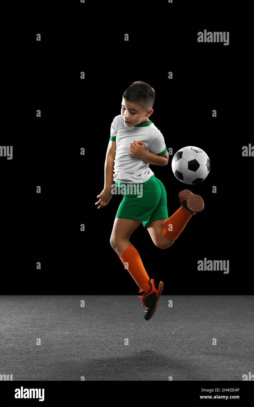 Full-length portrait of boy, child, football player in uniform training ...