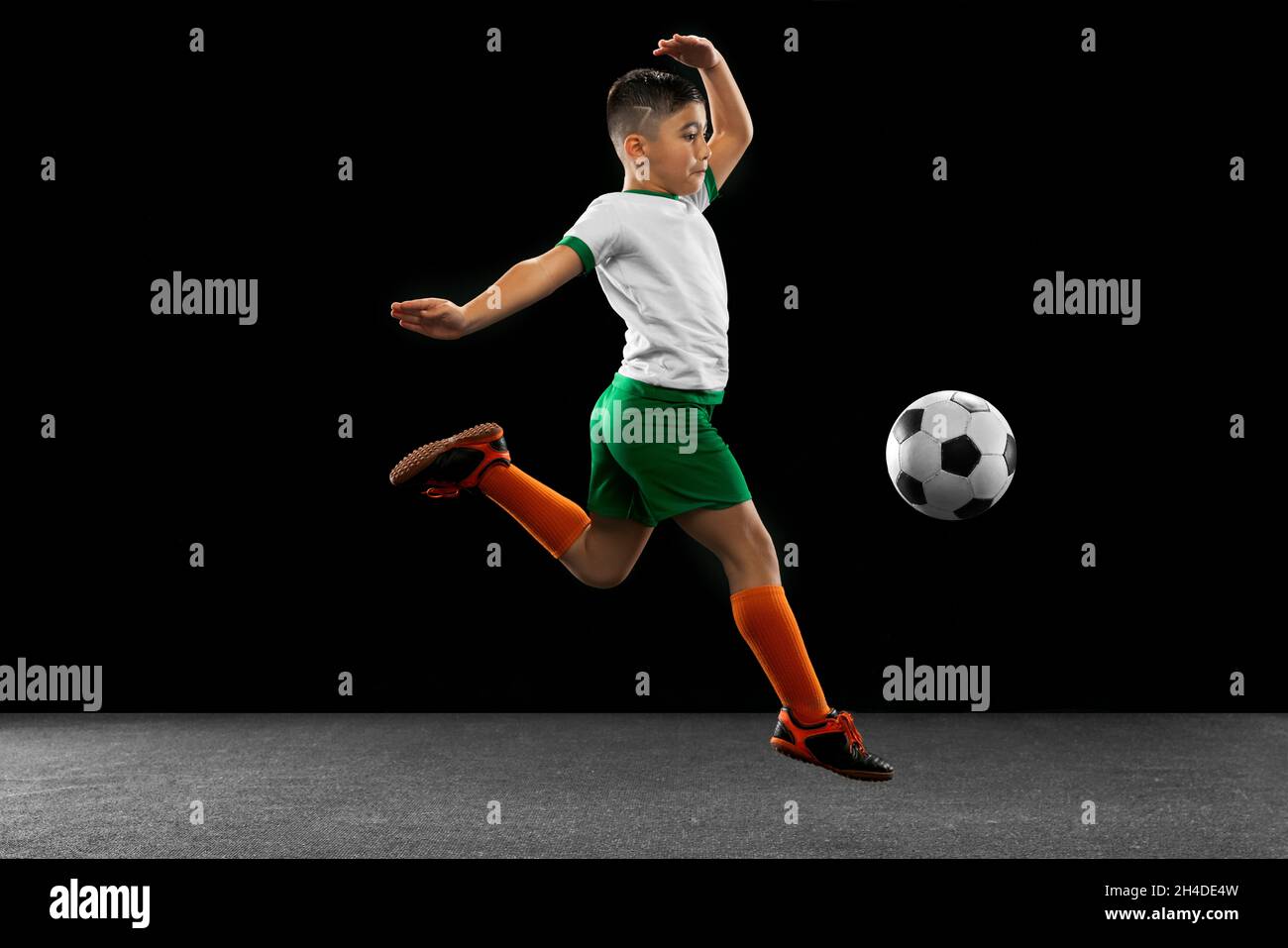 Full-length portrait of boy, child, football player in uniform training ...