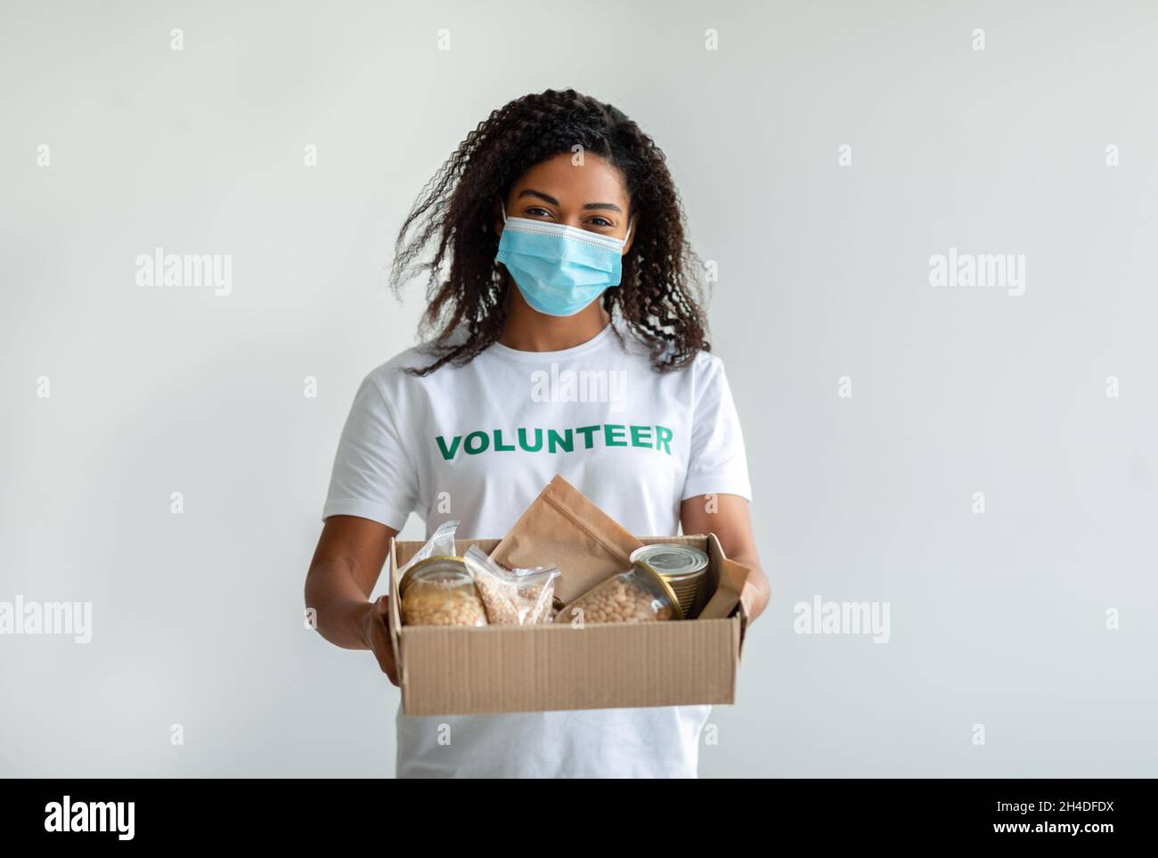 Young african american female volunteer in medical face mask holding ...