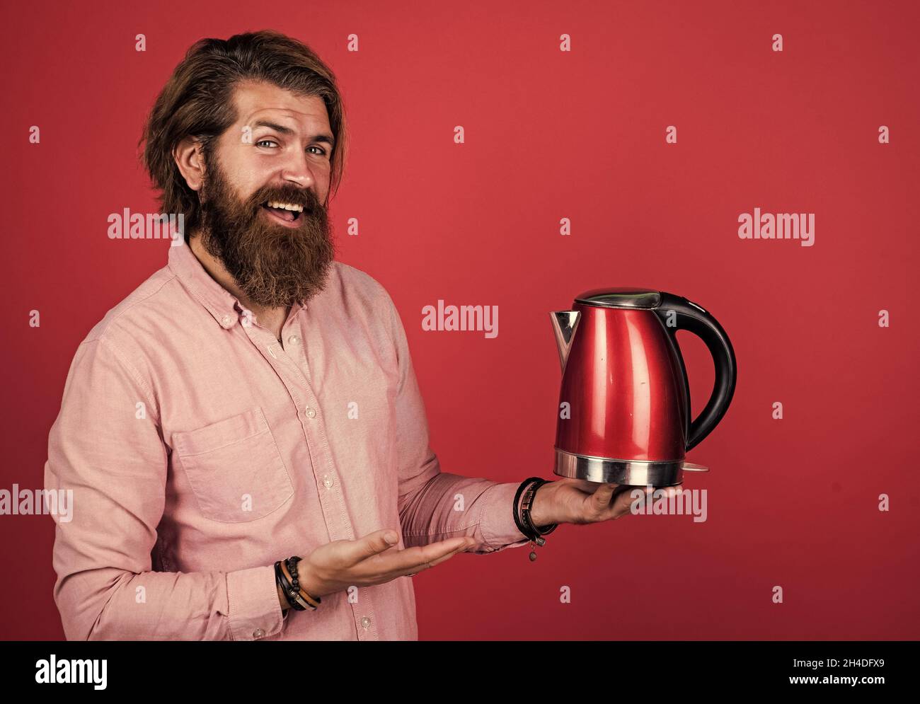handsome bearded guy with stylish hair use electric kettle, kitchen ...