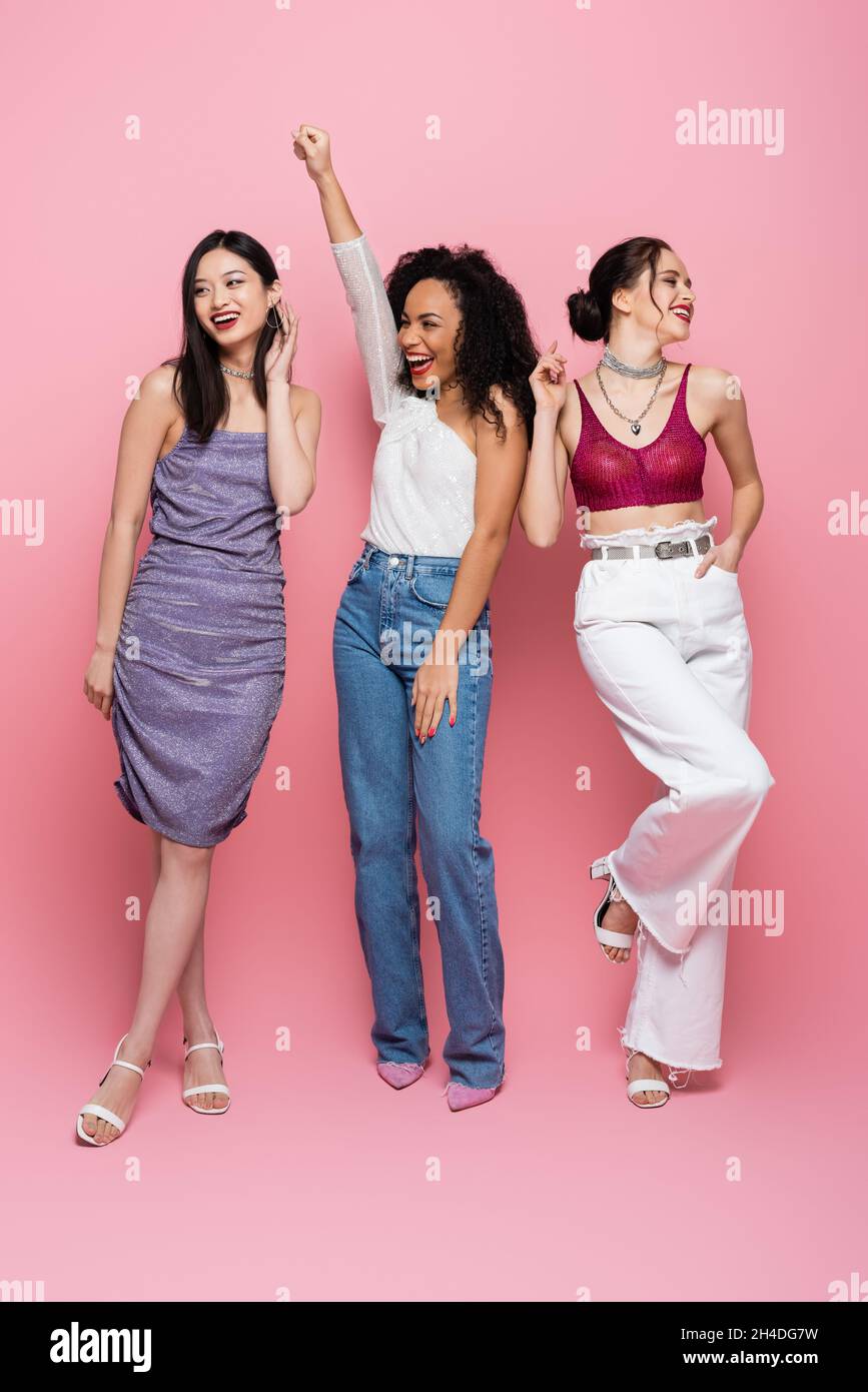 Full length of happy multicultural women posing during party on pink ...