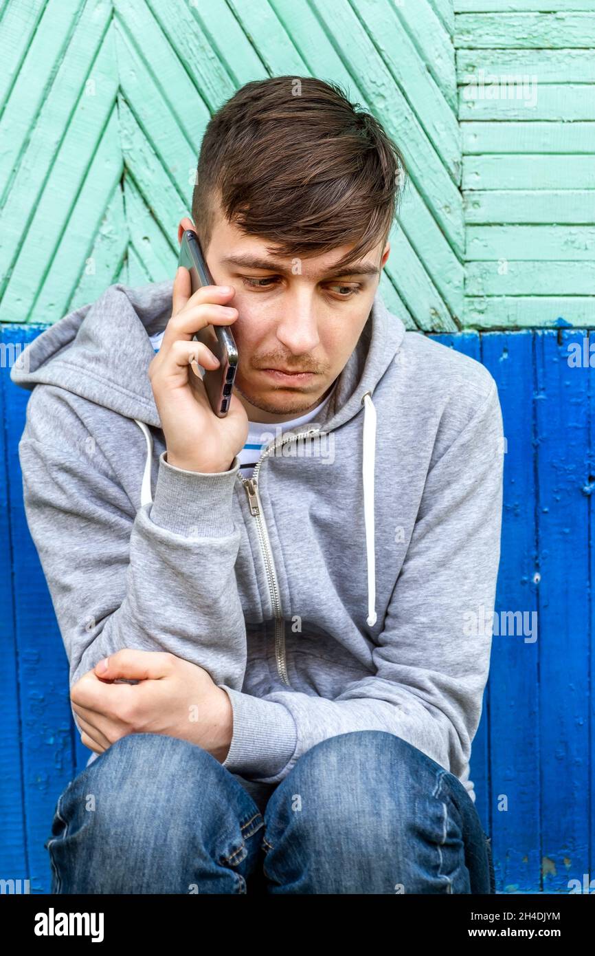 Sad Young Man call on the Phone on the Old Wall Background outdoor ...