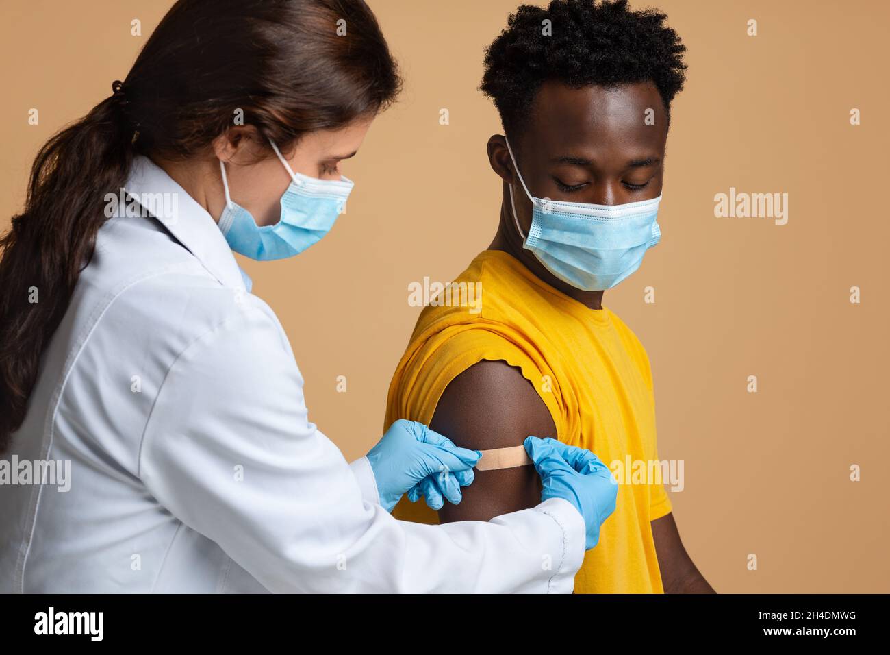 Female Nurse Applying Plaster On Black Guy's Shoulder After Injection ...