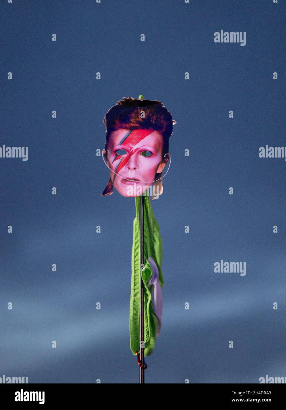 A David Bowie mask stands in the sky from the crowd at the Isle of ...