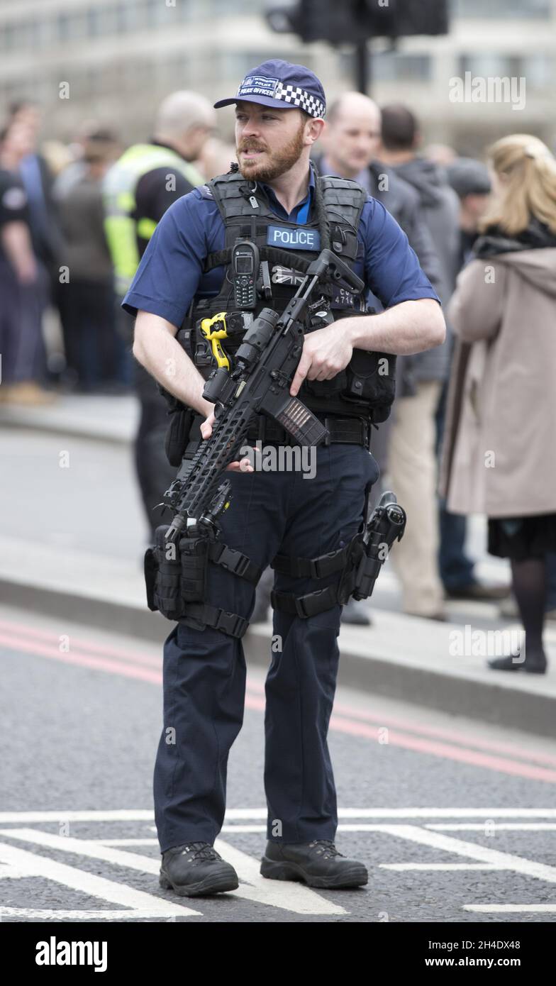 An armed police officer guard Westminster bridge, London, while people ...