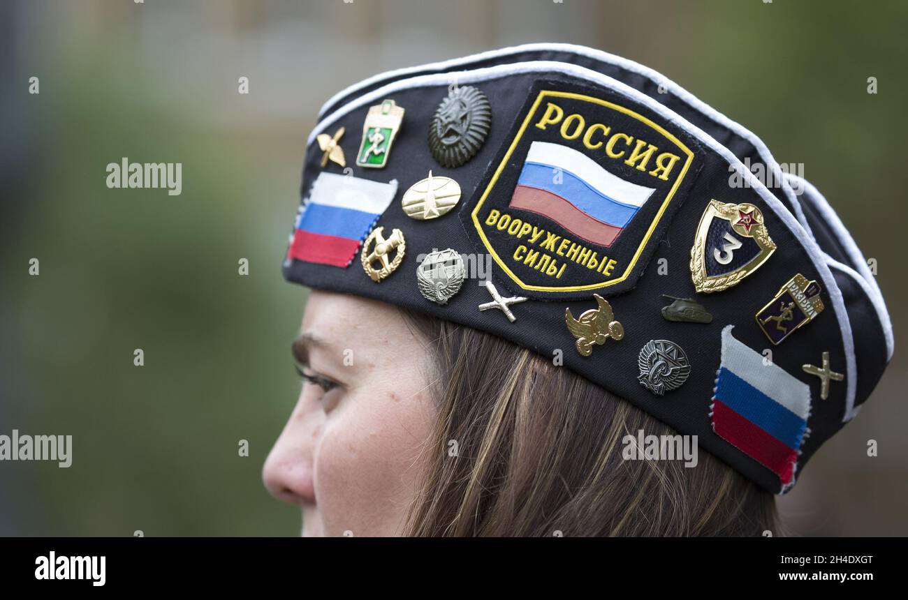 A woman wears Soviet War memorabilia badges on a vintage soldier's cap ...