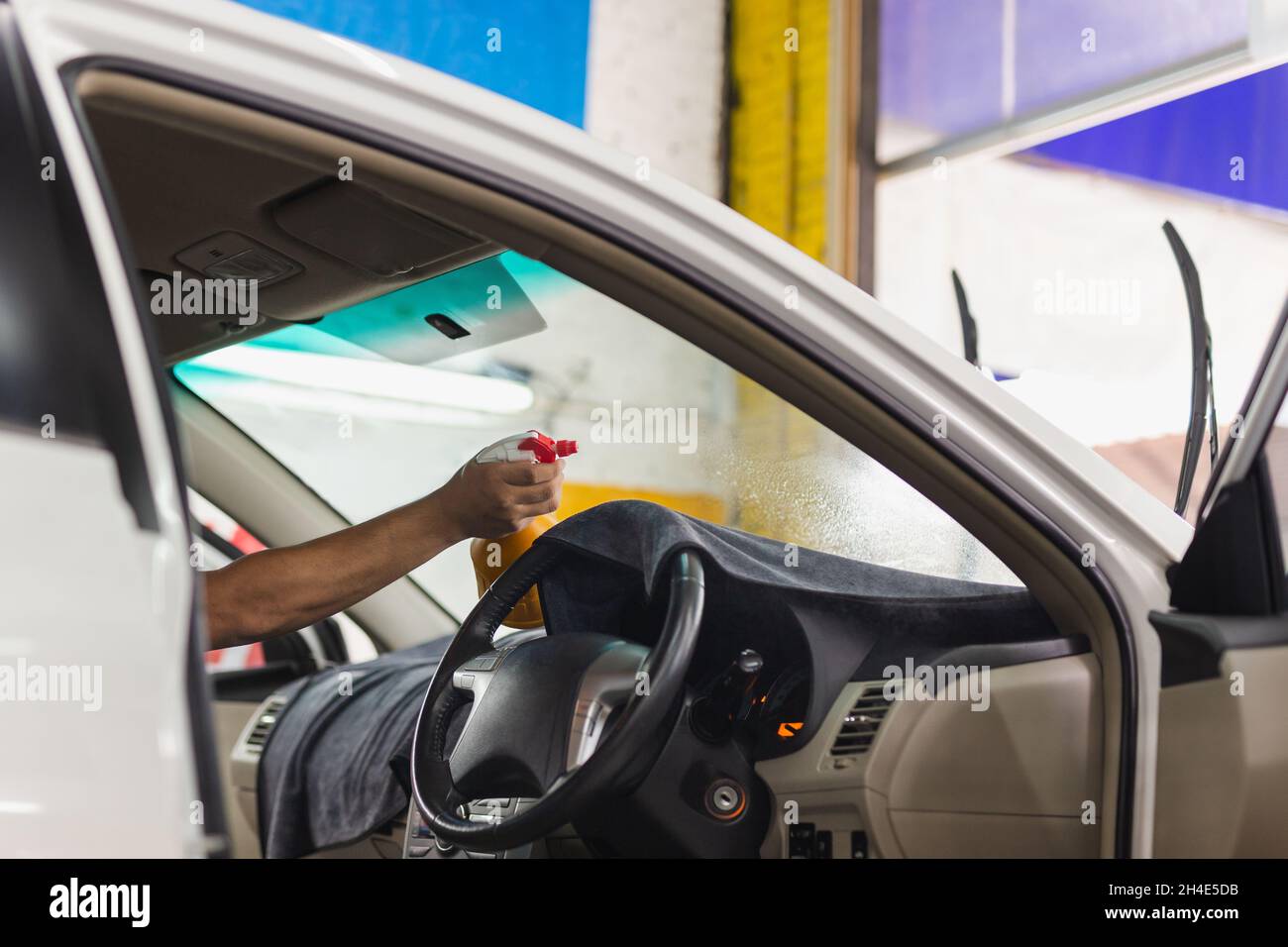 Man specialist spraying water into tinted car window in garage Stock ...