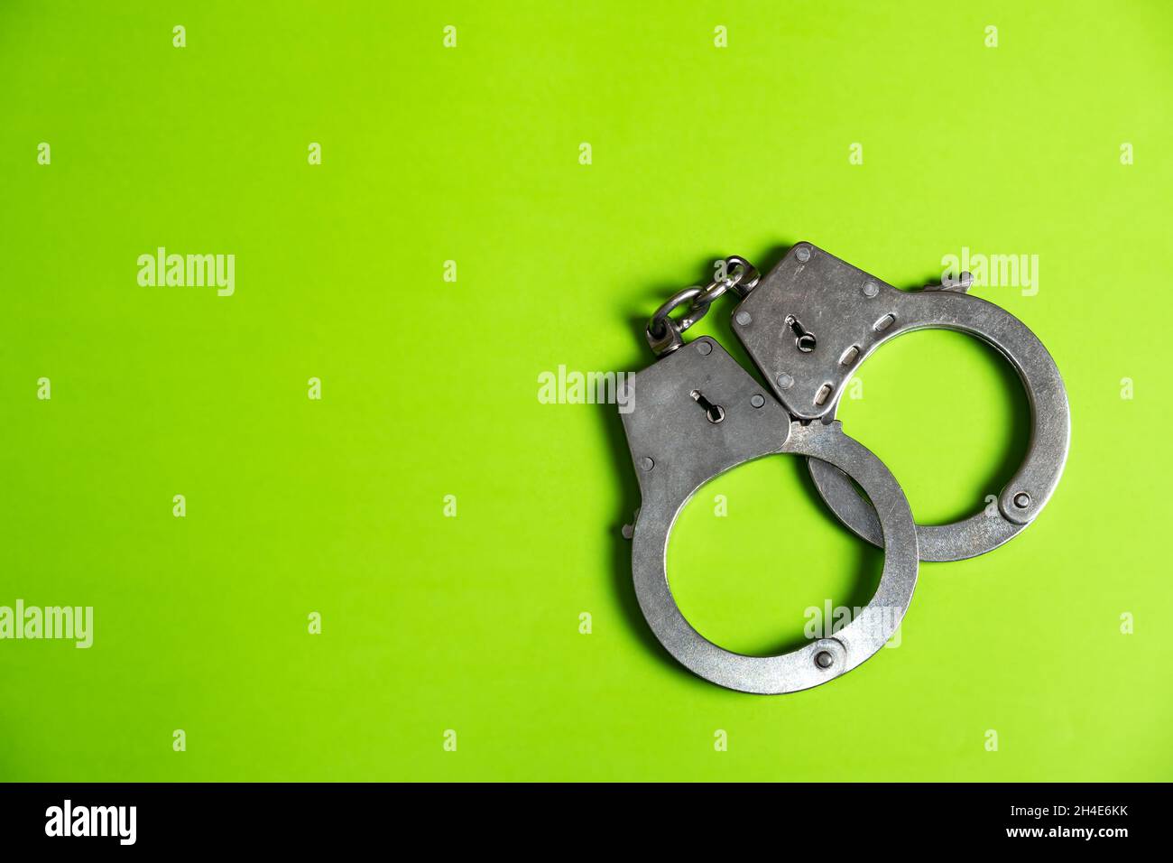 Handcuffs on the Green Paper Background closeup Stock Photo - Alamy