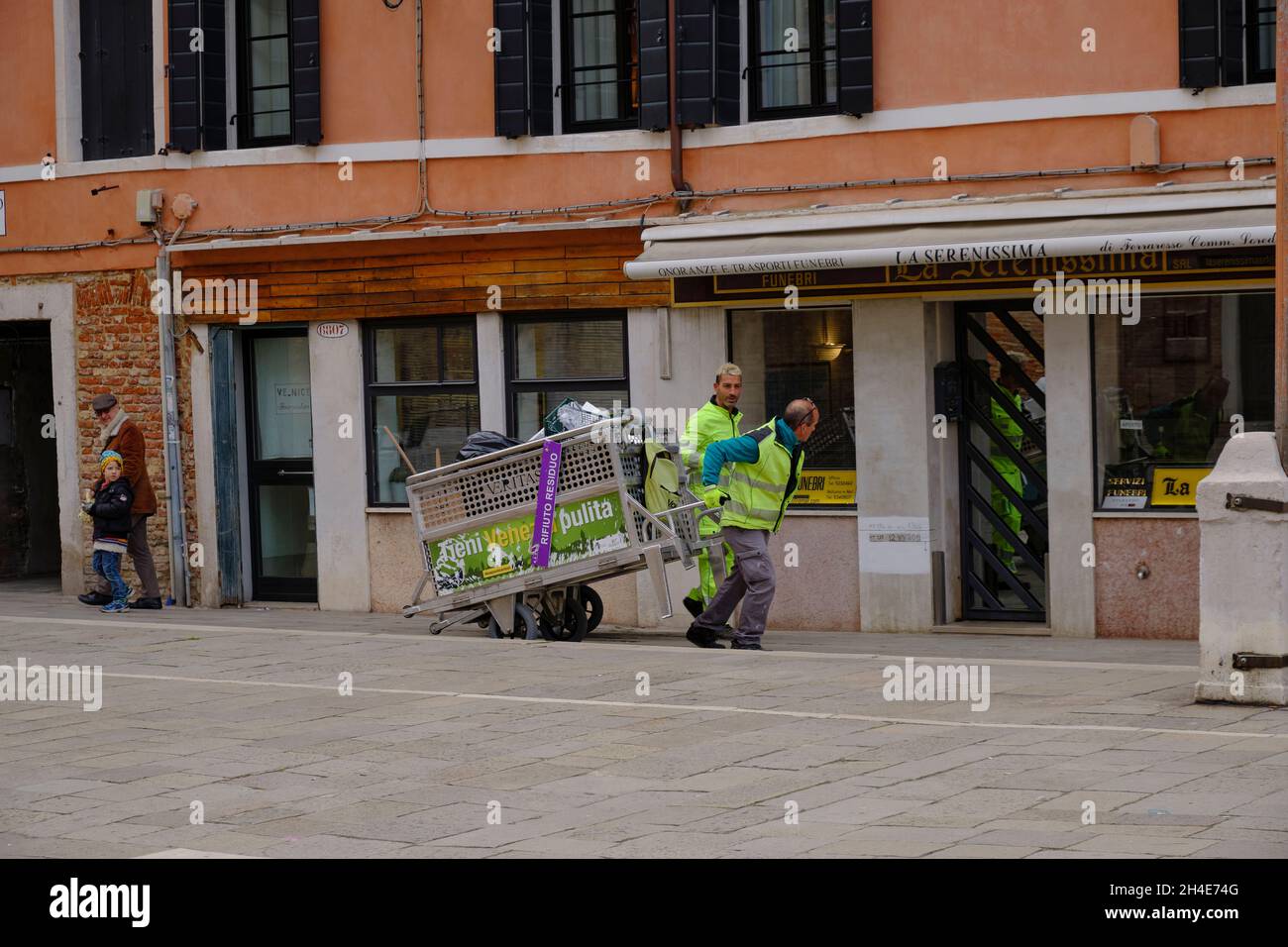 Bin men pulling rubbish cart through the streets of Venice in Italy ...